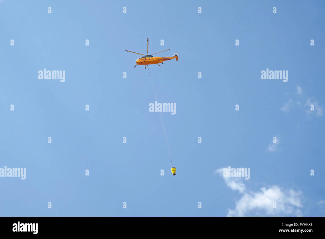 A yellow fire fighting helicopter flying to deliver water in Utah Stock ...