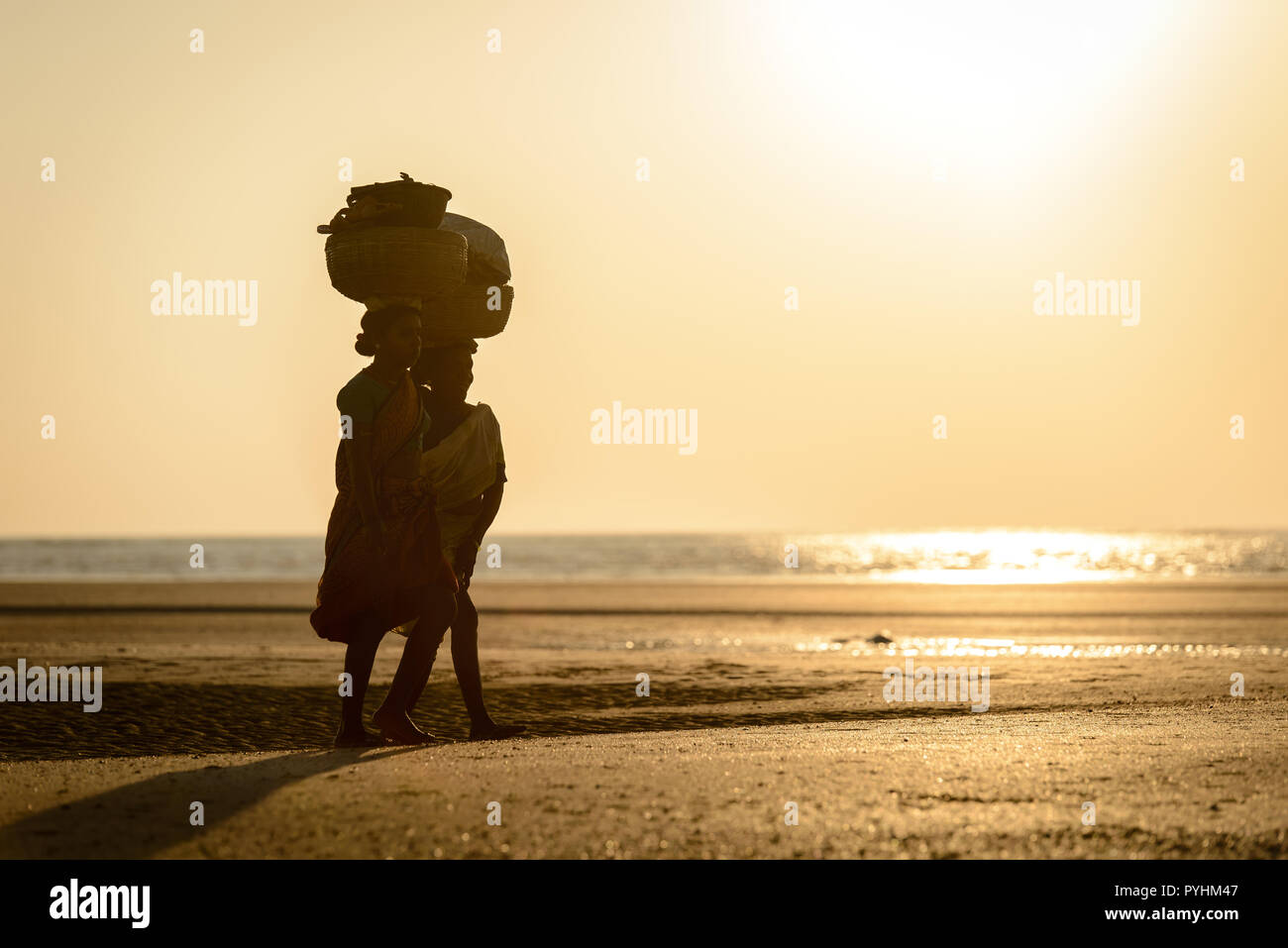 Black silhouette of women carrying catch on their heads walking along ...