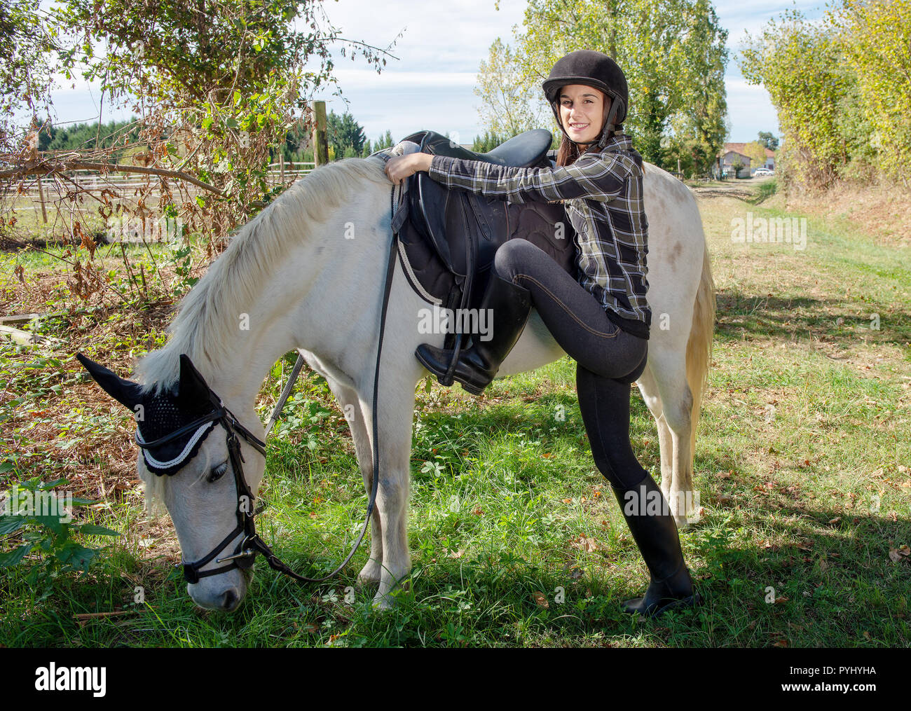 a young woman rider mounting a white horse Stock Photo - Alamy