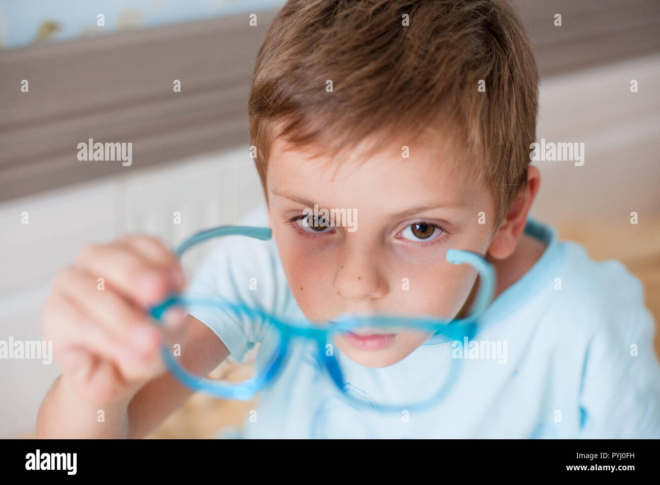 cute little boy watching on blue glasses in his hand sitting at home ...