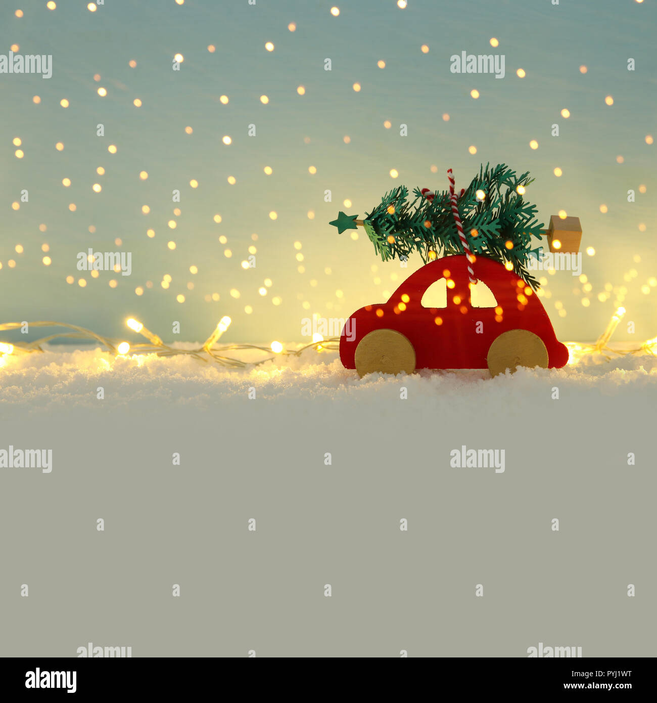Red wooden car carrying a christmas tree over snow in front of blue ...