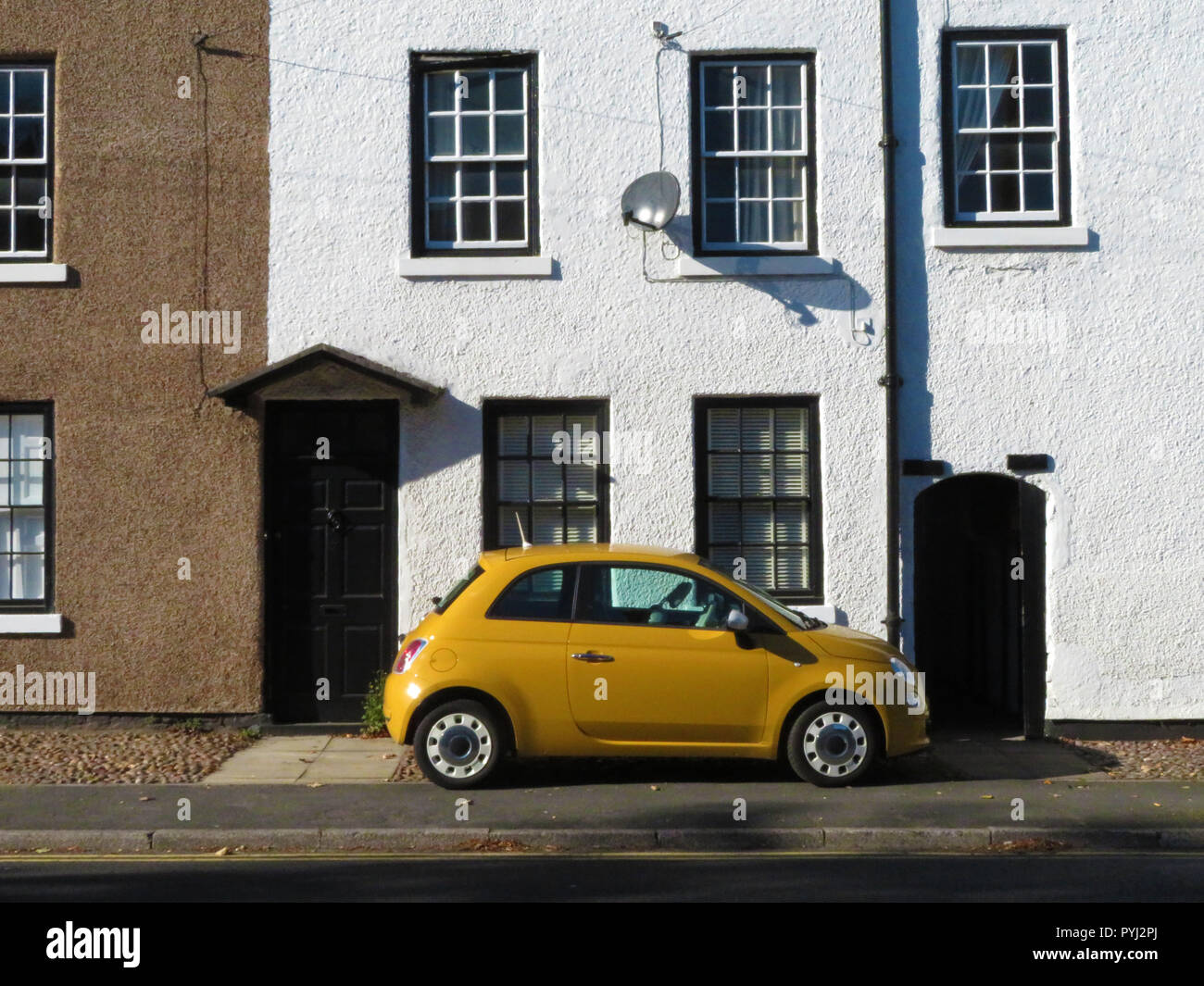 Small yellow Fiat car parked outside a terraced house in a street in ...
