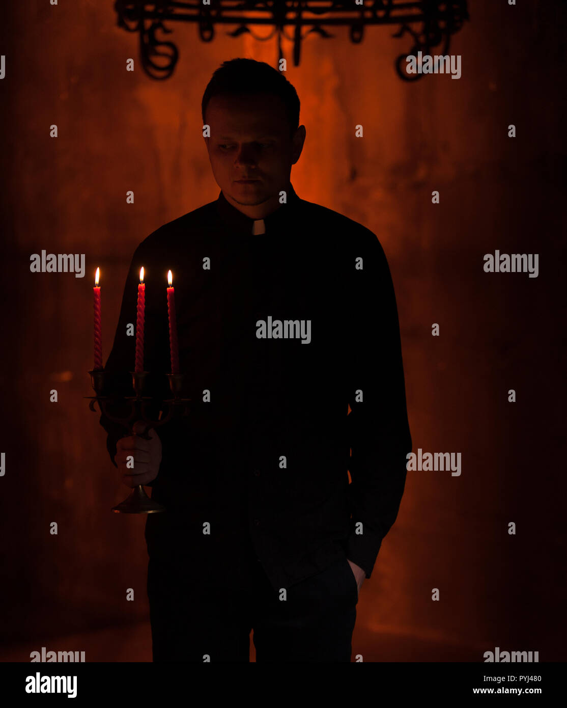 Young Catholic Praying priest. Portrait of priest Next to the candles ...