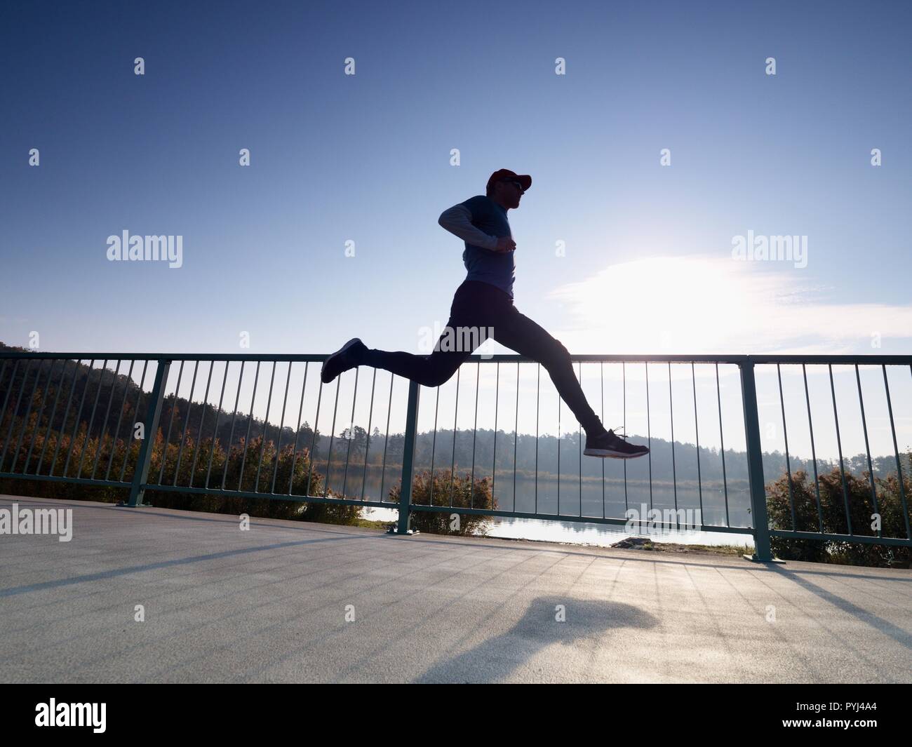 Side view silhouette of a runner man running on the beach bridge at ...