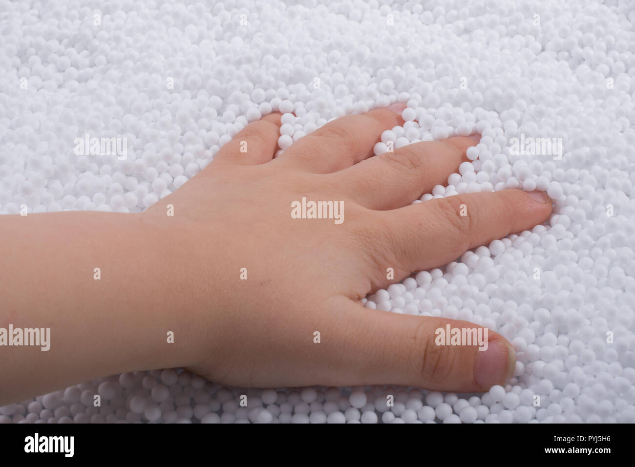 Toddler hand in White polystyrene foam balls as background Stock Photo ...