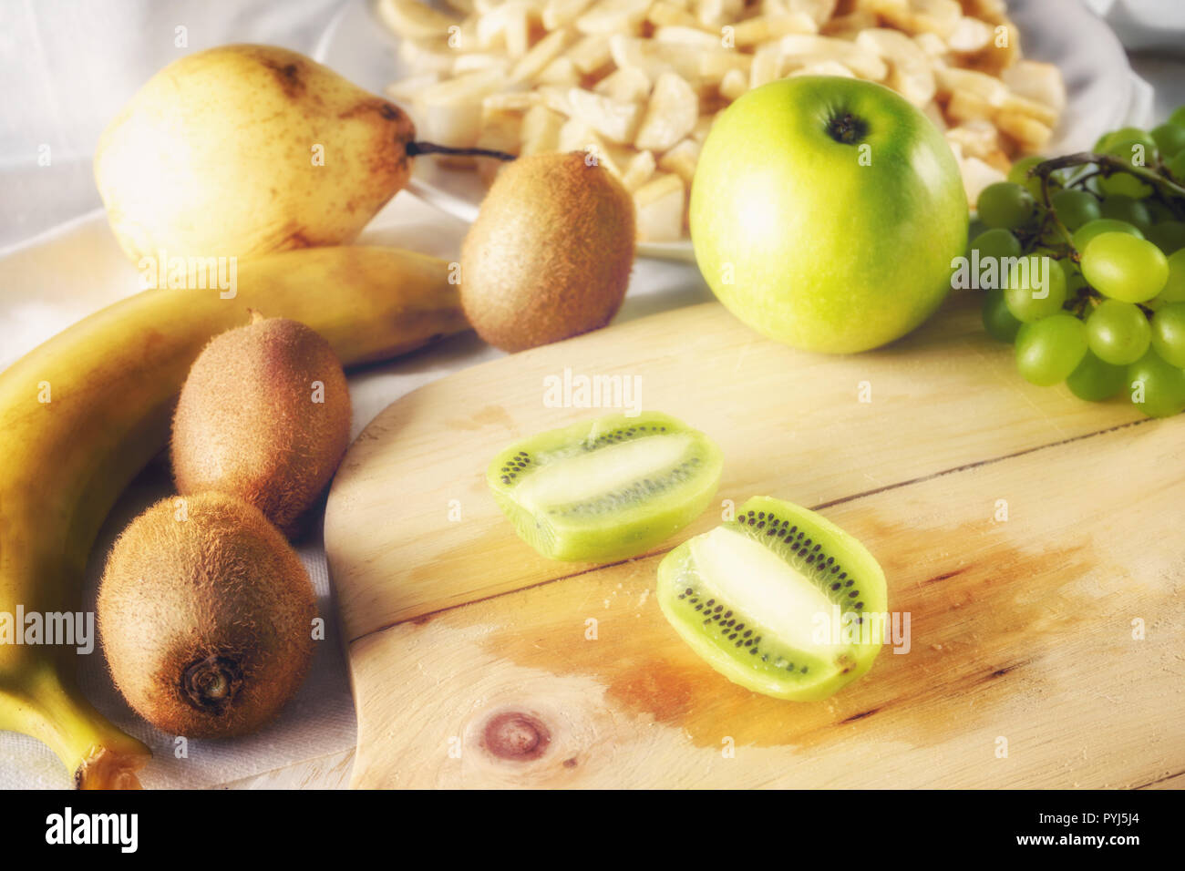 Ingredients for fruit salad. Cutting kiwi Stock Photo - Alamy
