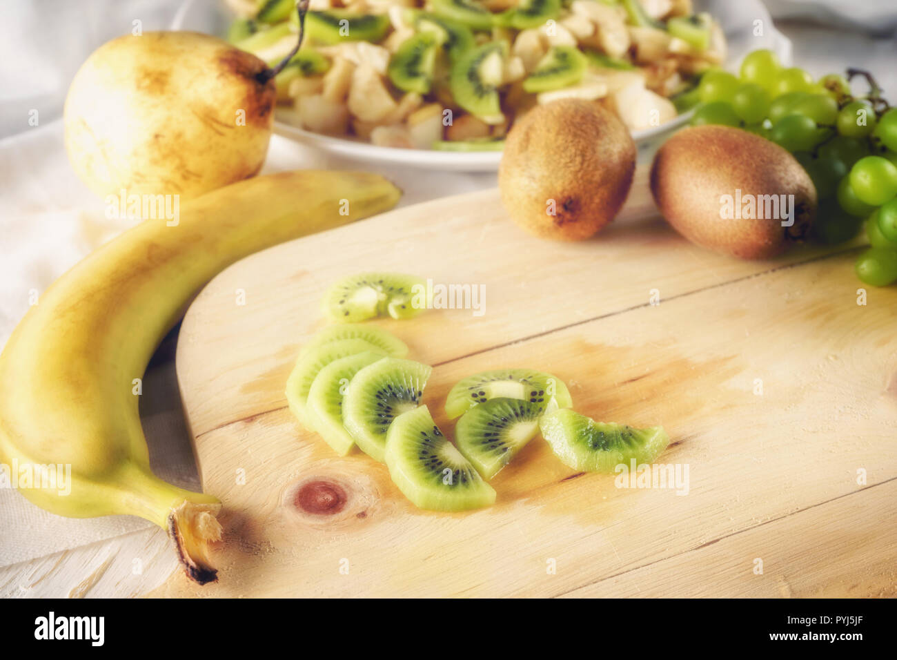 Ingredients for fruit salad. Cutting kiwi Stock Photo - Alamy
