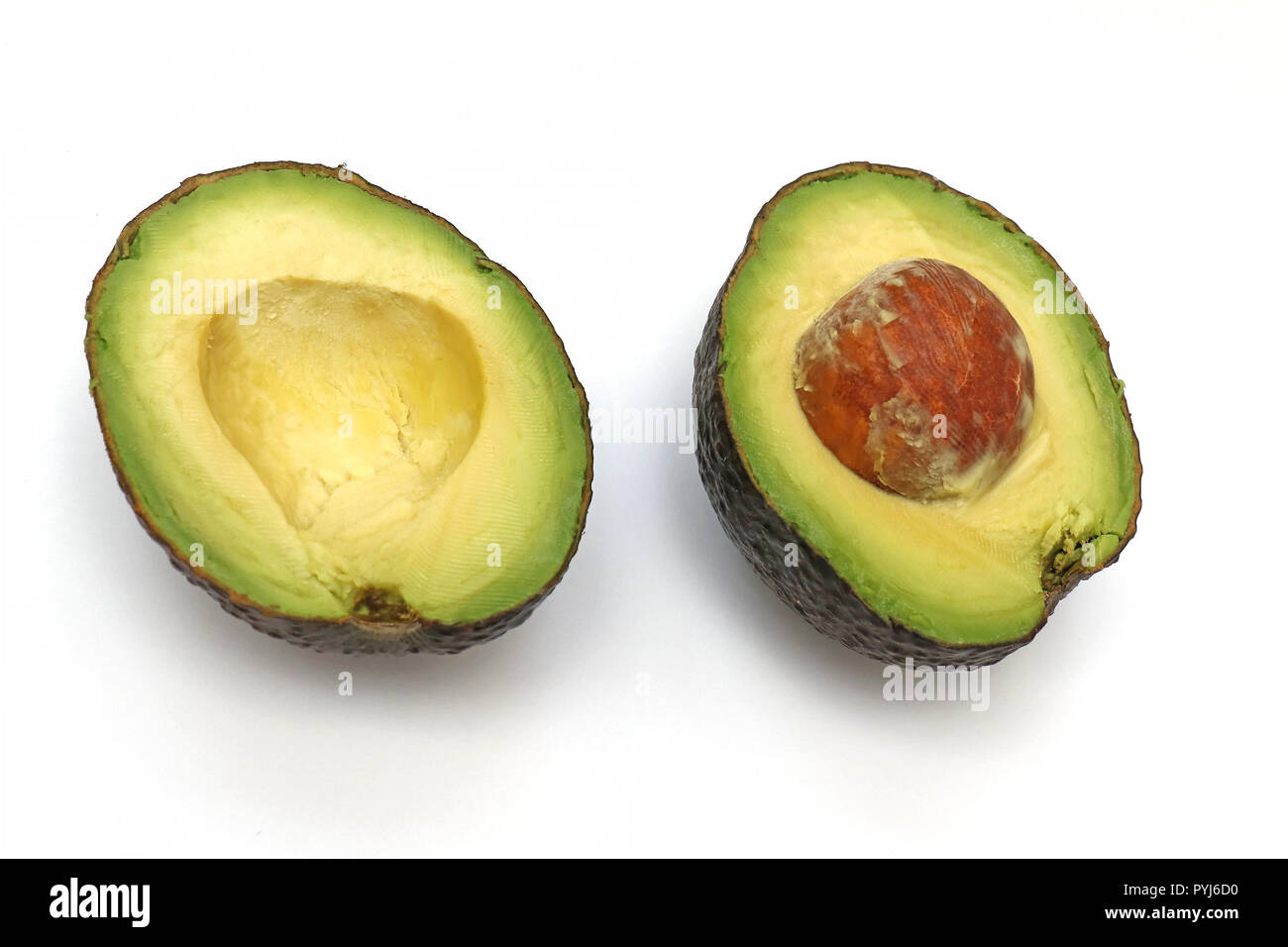 Organic ripe avocado cut in half on white background Stock Photo - Alamy