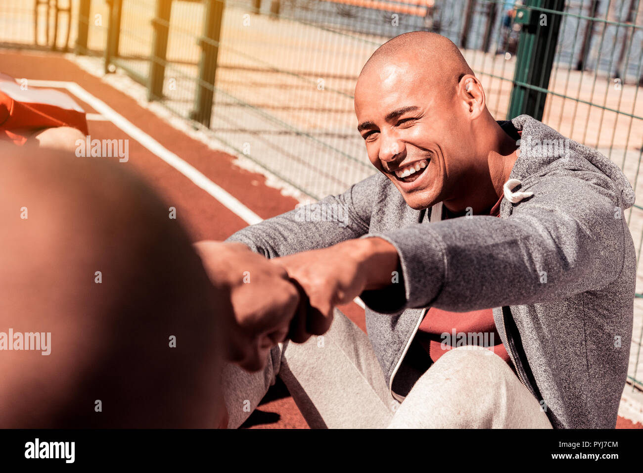 Joyful positive man touching his friends hand Stock Photo - Alamy