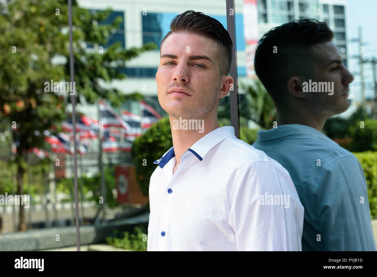 Young handsome man leaning against glass window of modern buildi Stock ...