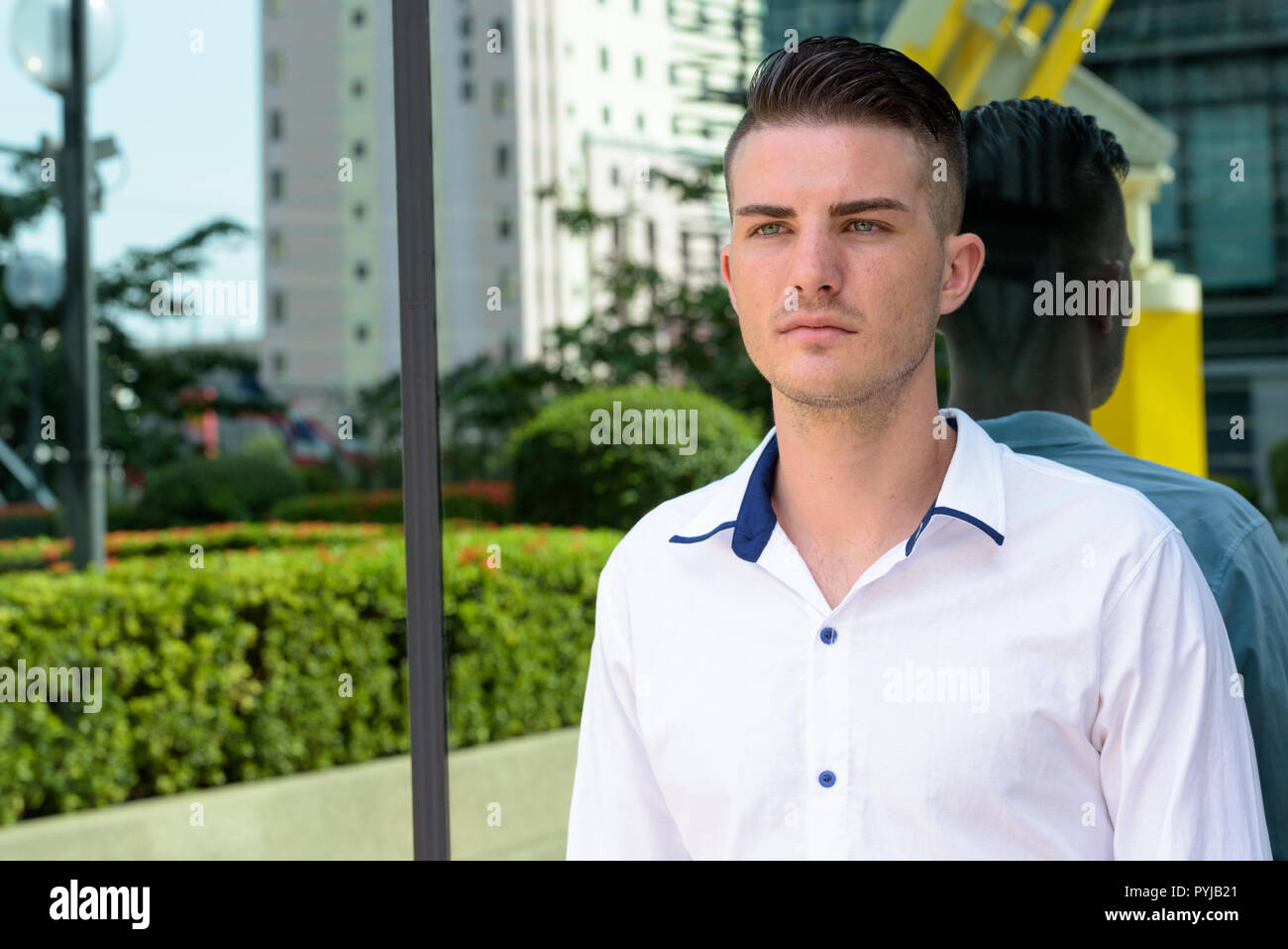Young handsome man thinking against glass window of modern build Stock ...