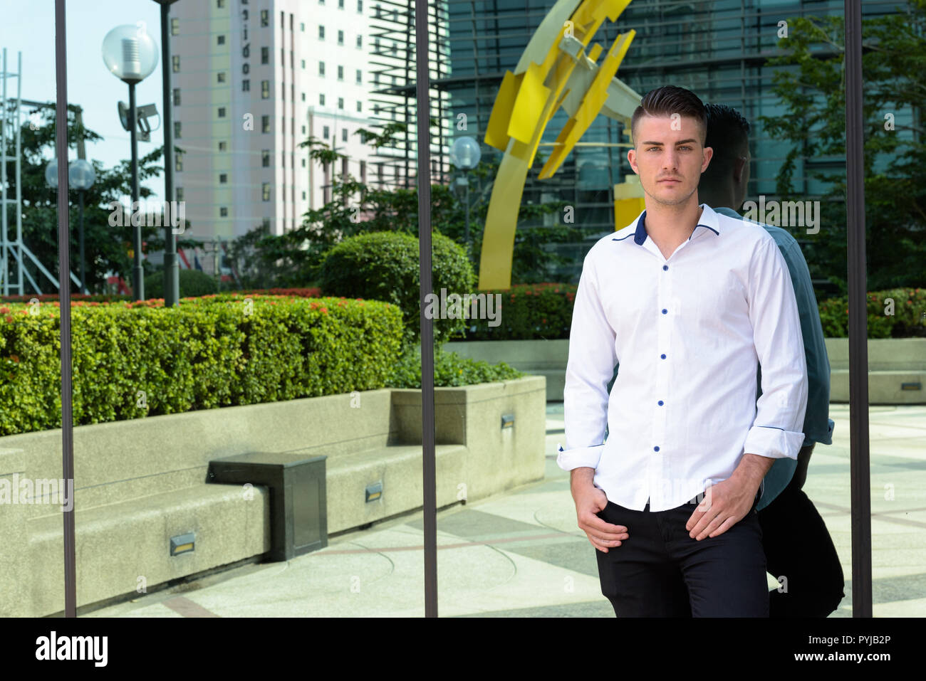 Young handsome man standing and leaning against glass window of Stock ...