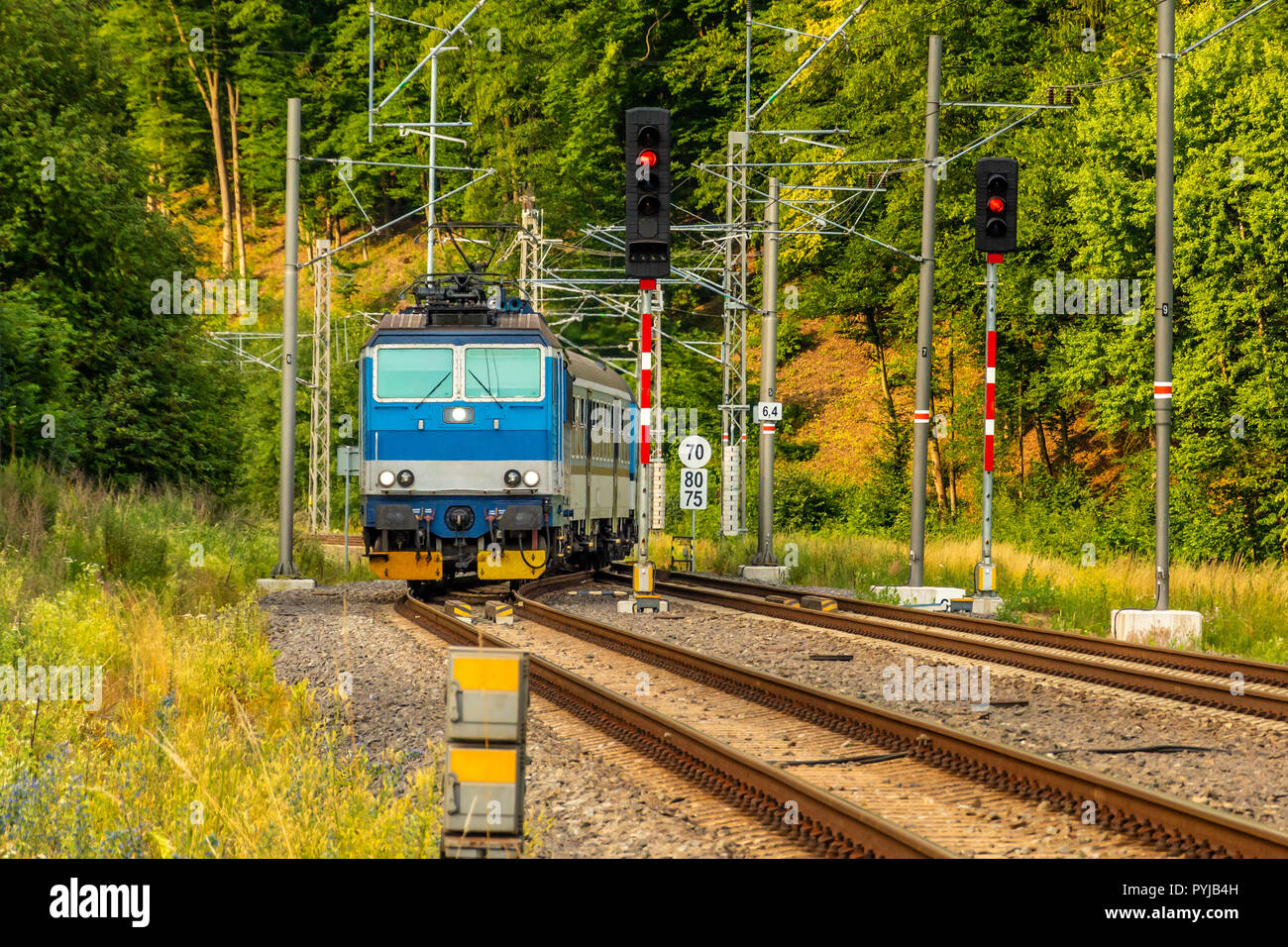 A blue electric locomotive passing the Czech countryside. A train ...