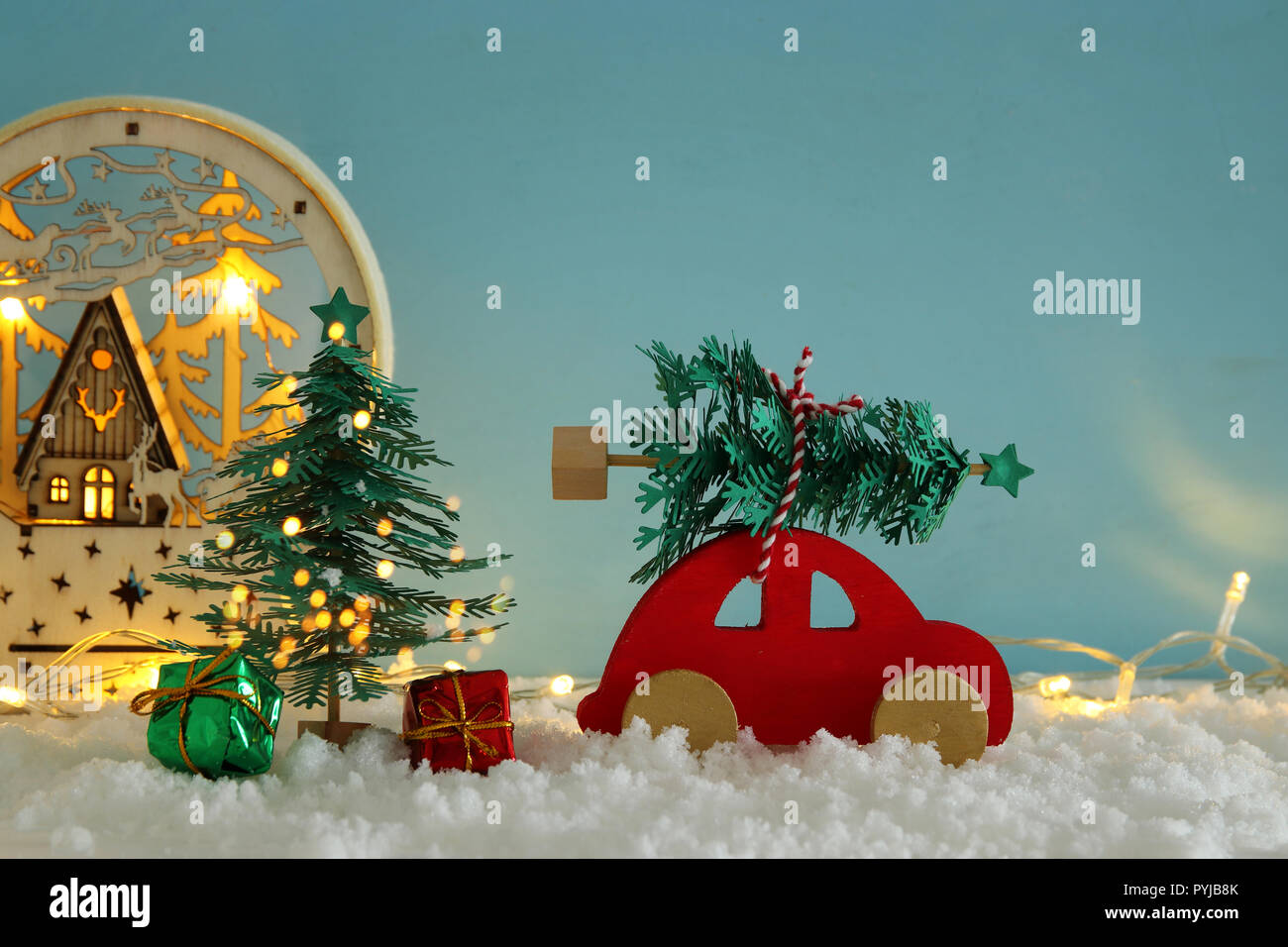 Red wooden car carrying a christmas tree over snow in front of blue ...