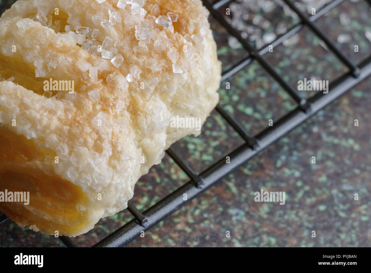 puff pastry with large crystals of coarse sugar on a black baking rack ...