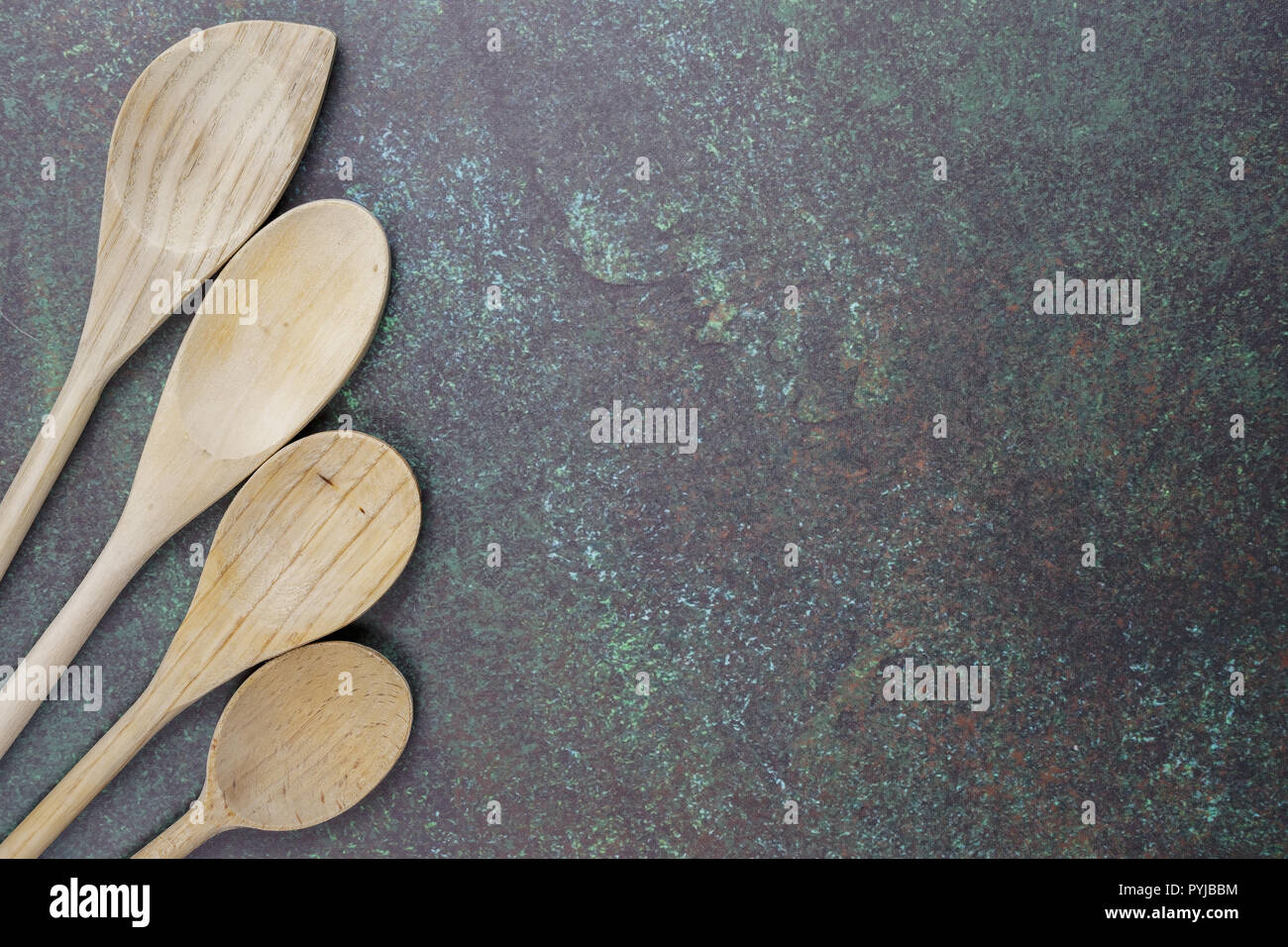 left side border of wooden spoons on blue green patterned countertop ...