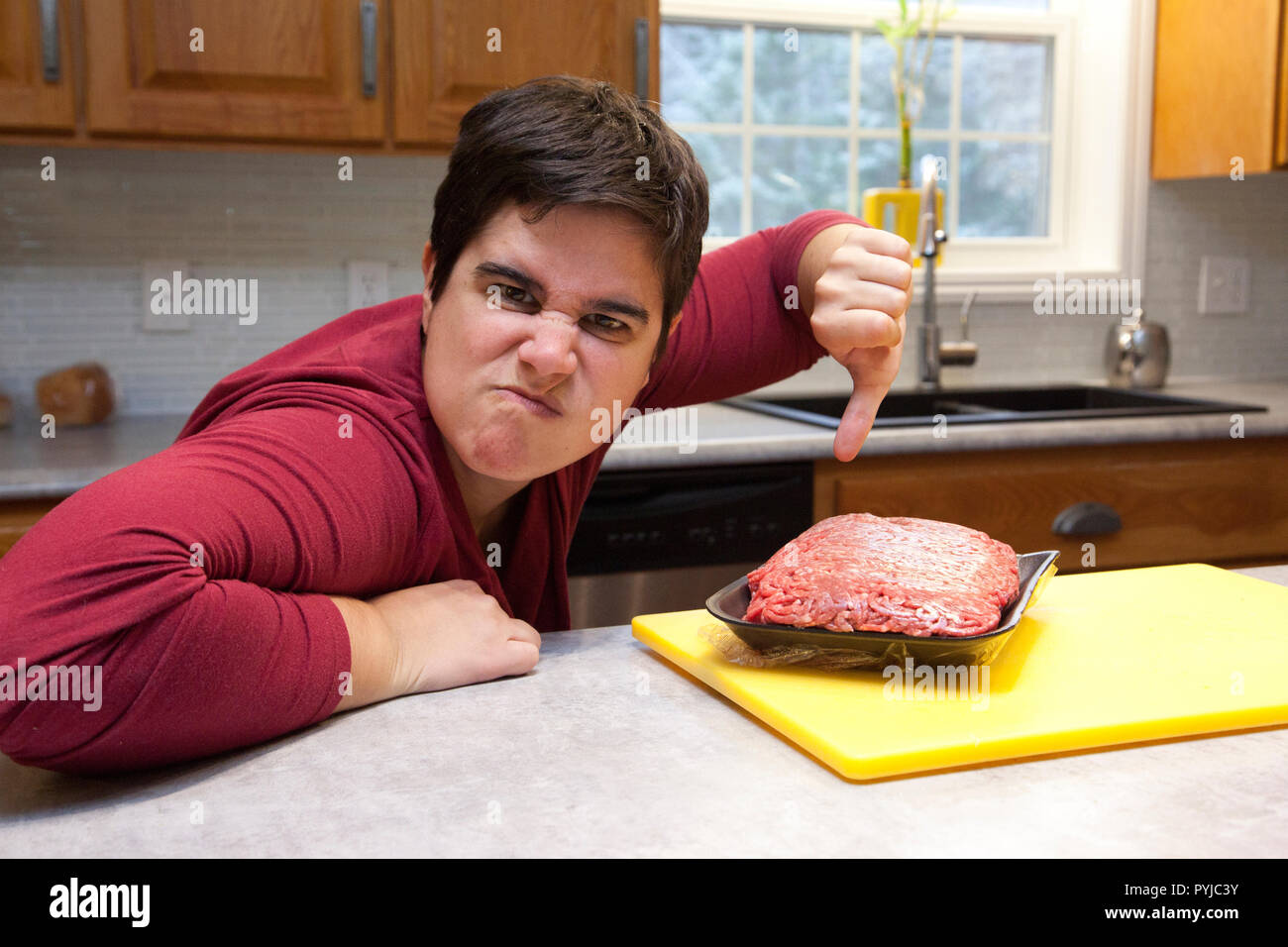 Giving thumbs down to a package of ground beef in the kitchen Stock ...