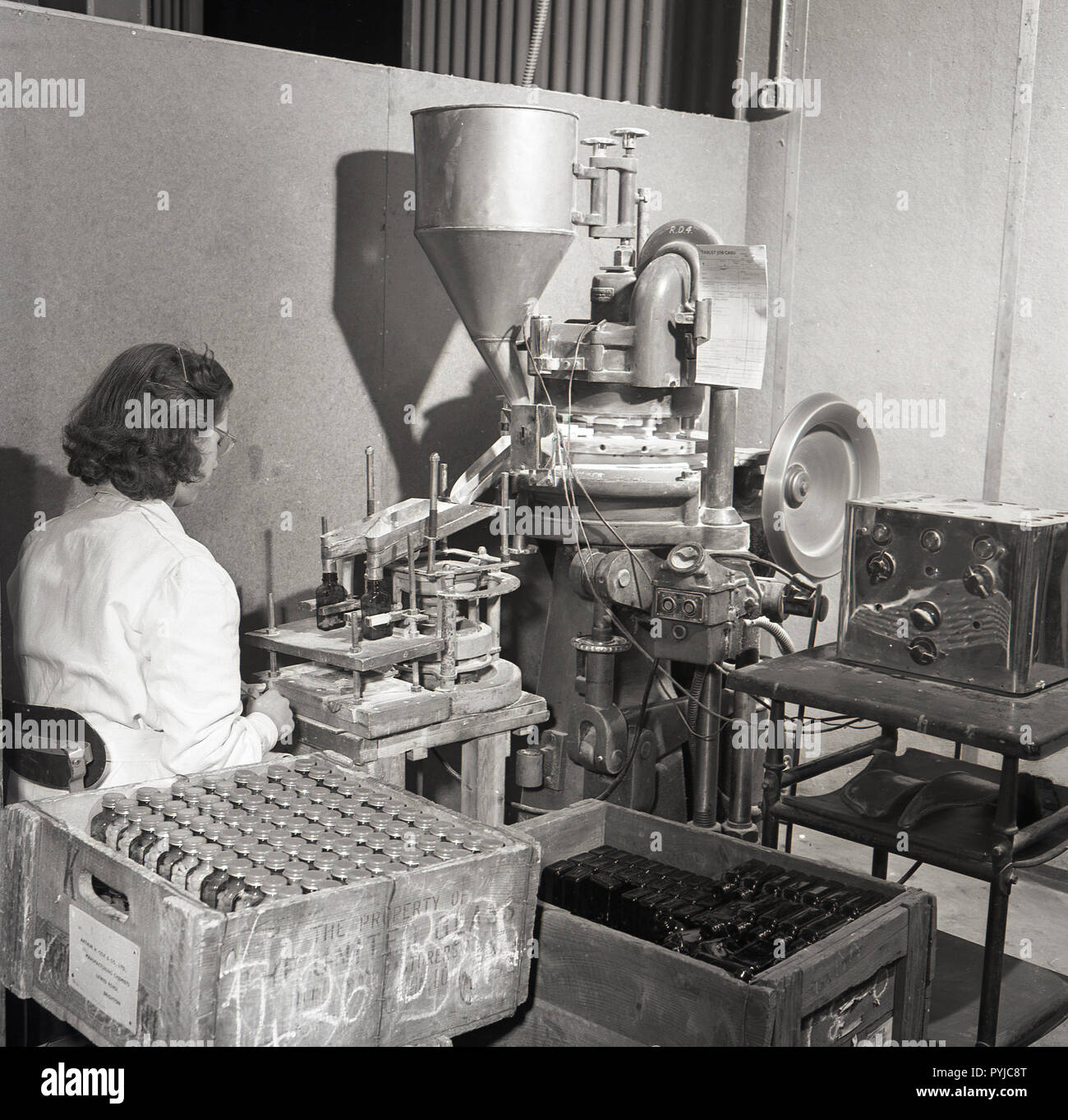 1950s, historical, a white-coated female sitting working at medicines ...