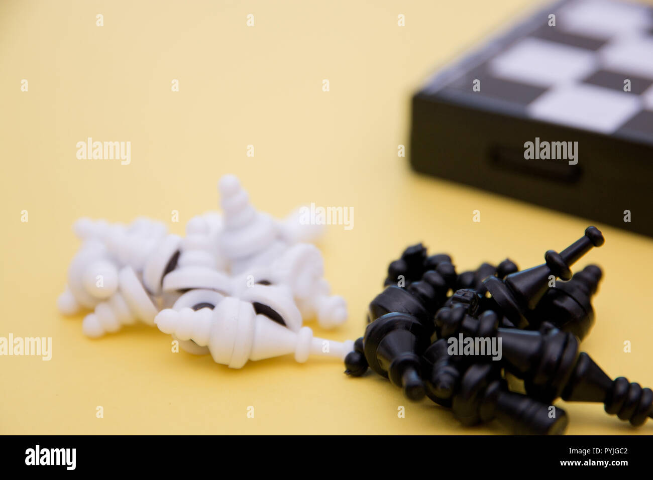 small chess pieces black and white on yellow background Stock Photo - Alamy