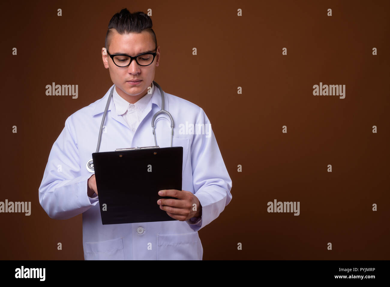 Young handsome multi-ethnic man doctor against brown background Stock ...