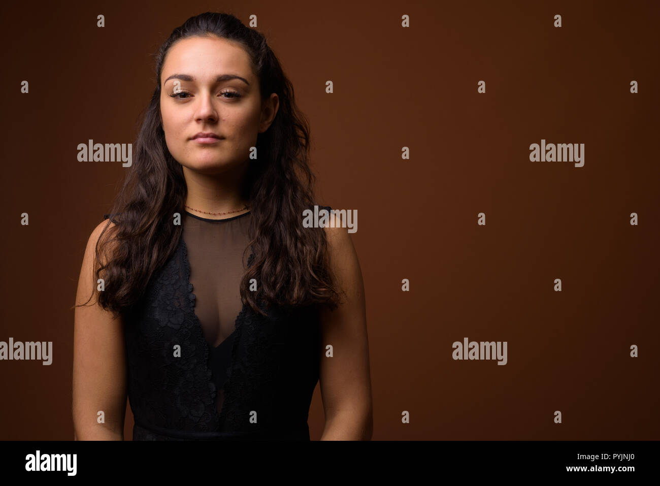 Studio shot of young beautiful woman against brown background Stock ...
