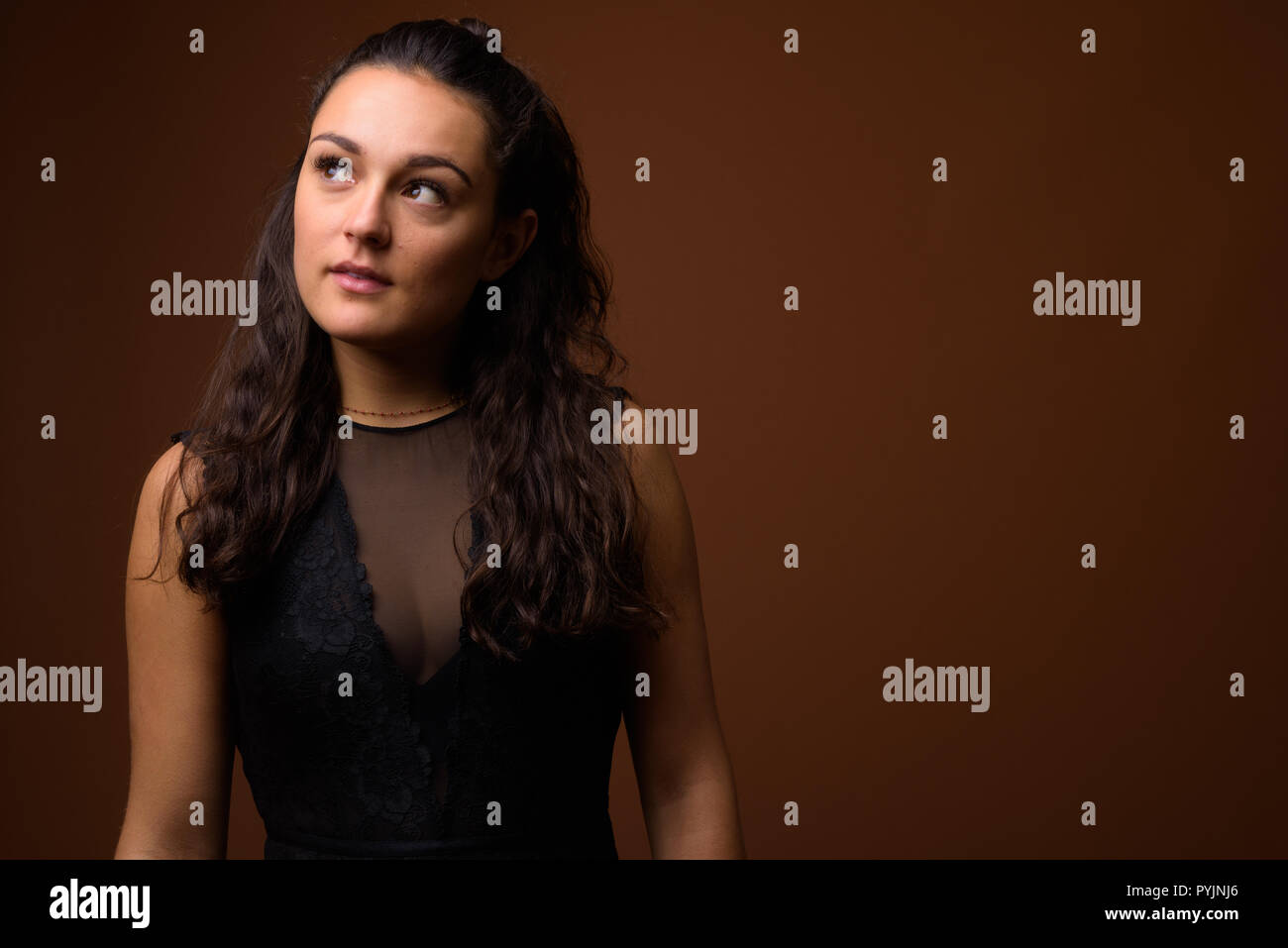 Studio shot of young beautiful woman against brown background Stock ...
