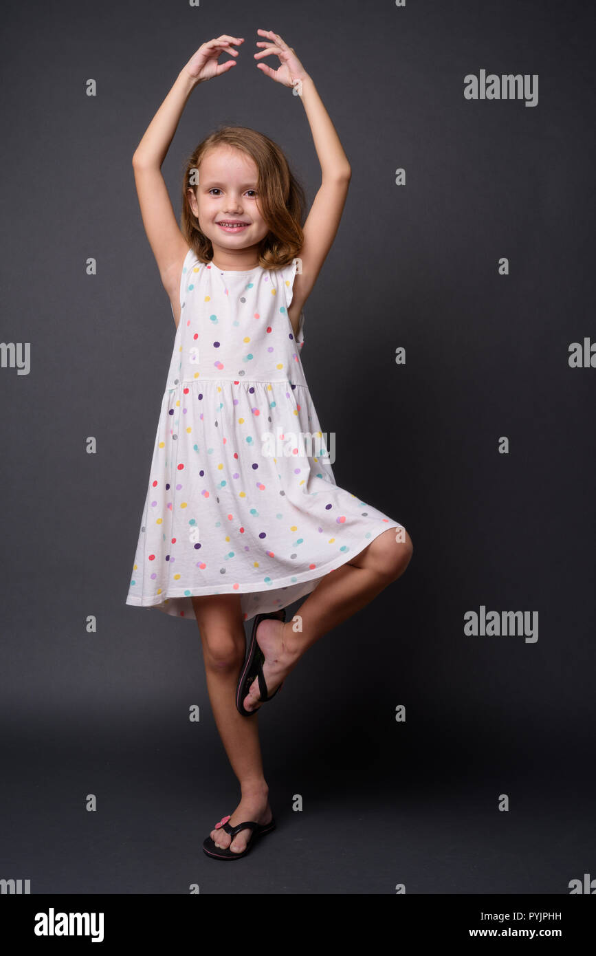 Cute young girl with blond hair against gray background Stock Photo - Alamy