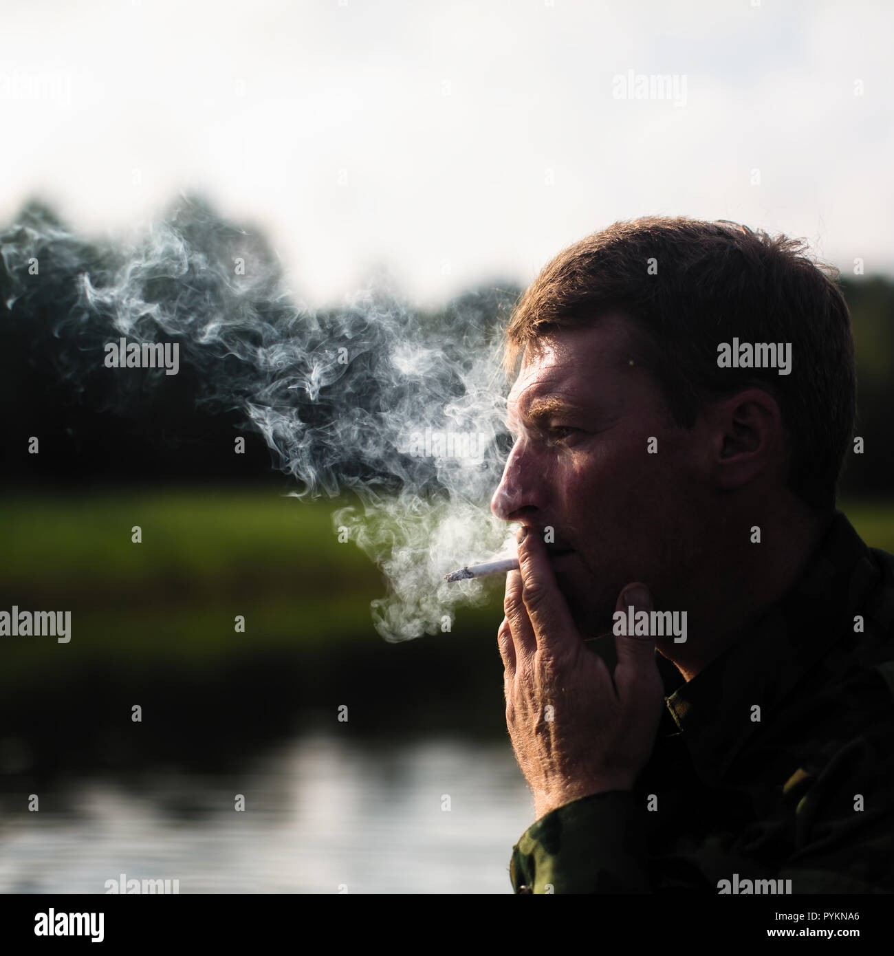 Man smoking outdoor, close-up. Smoke in the background light Stock ...