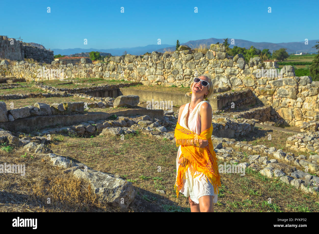 Nice tourist woman in Greek dress smiling mischievous at Historic Site ...