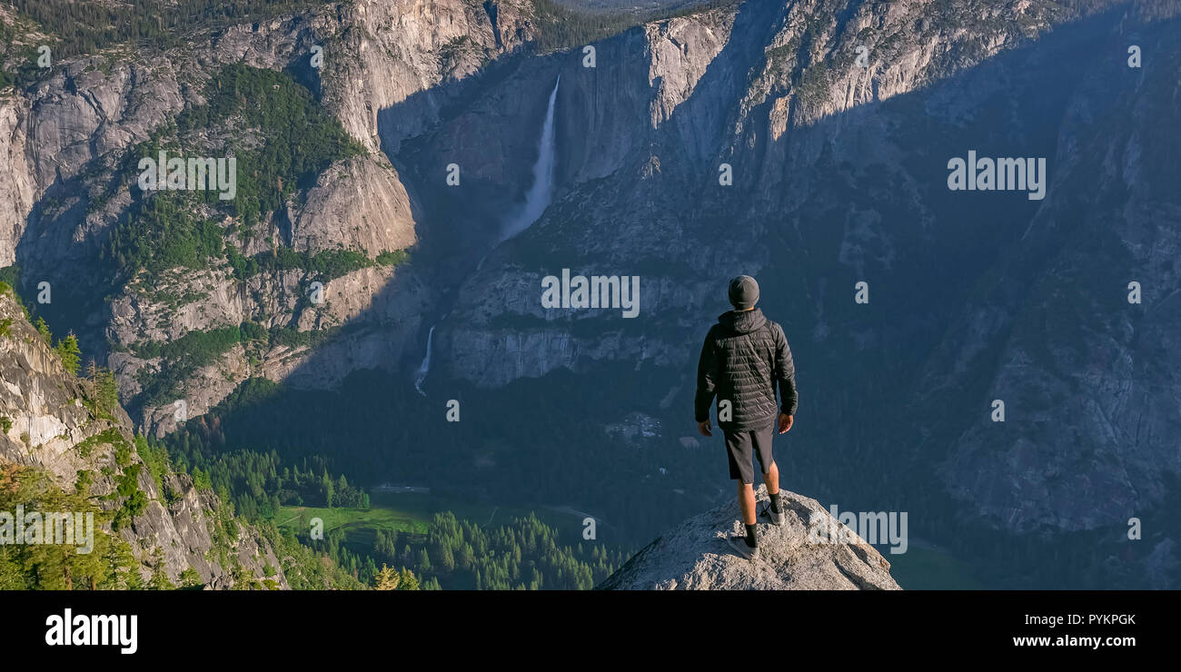 Man on cliff overlooking Yosemite Falls and valley Stock Photo - Alamy