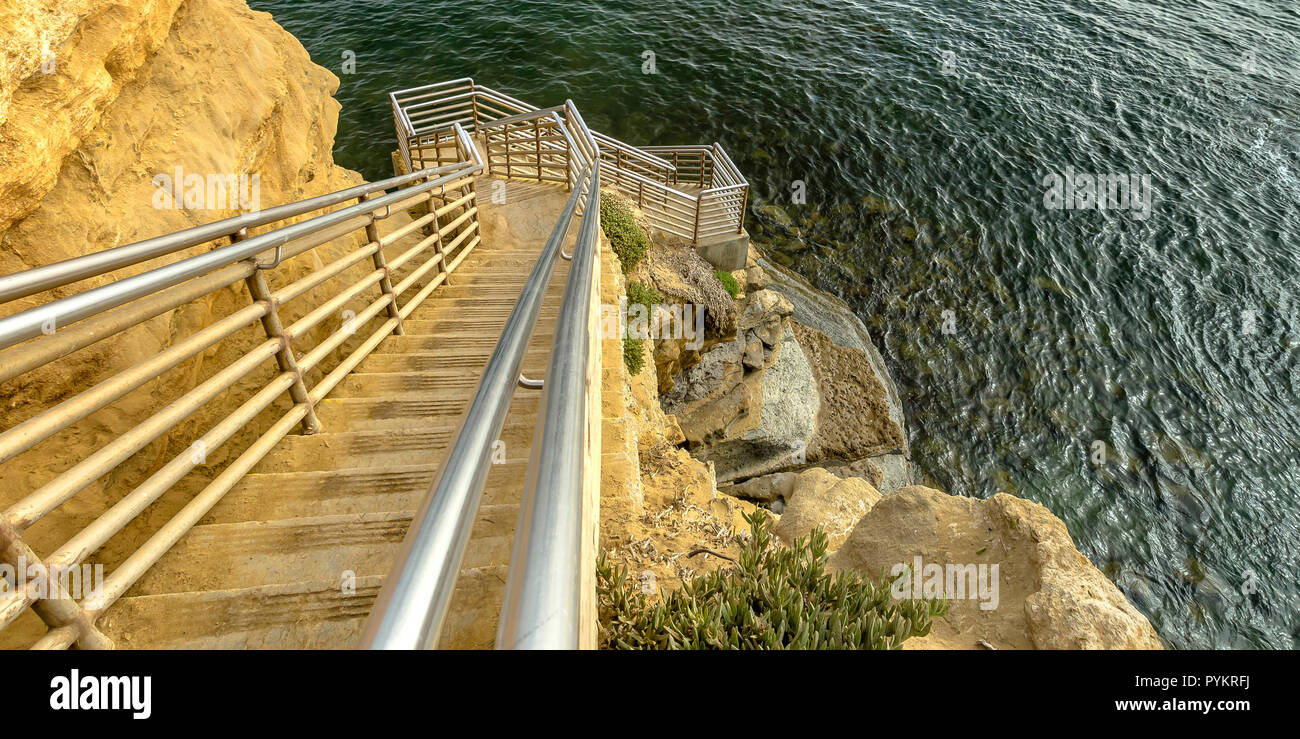 Sunlit stairs on a cliff going down the calm ocean Stock Photo - Alamy