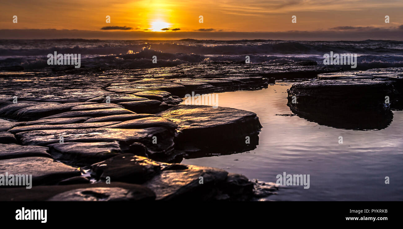 Tide pools with the sun setting in the horizon Stock Photo - Alamy