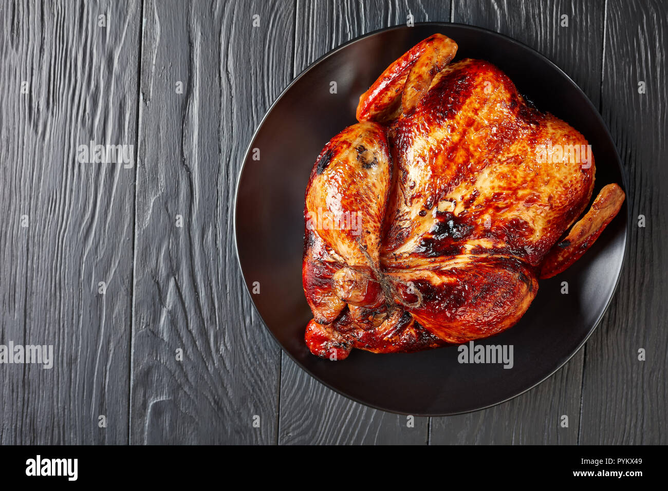 whole roasted chicken with golden brown crispy skin on a black plate on ...
