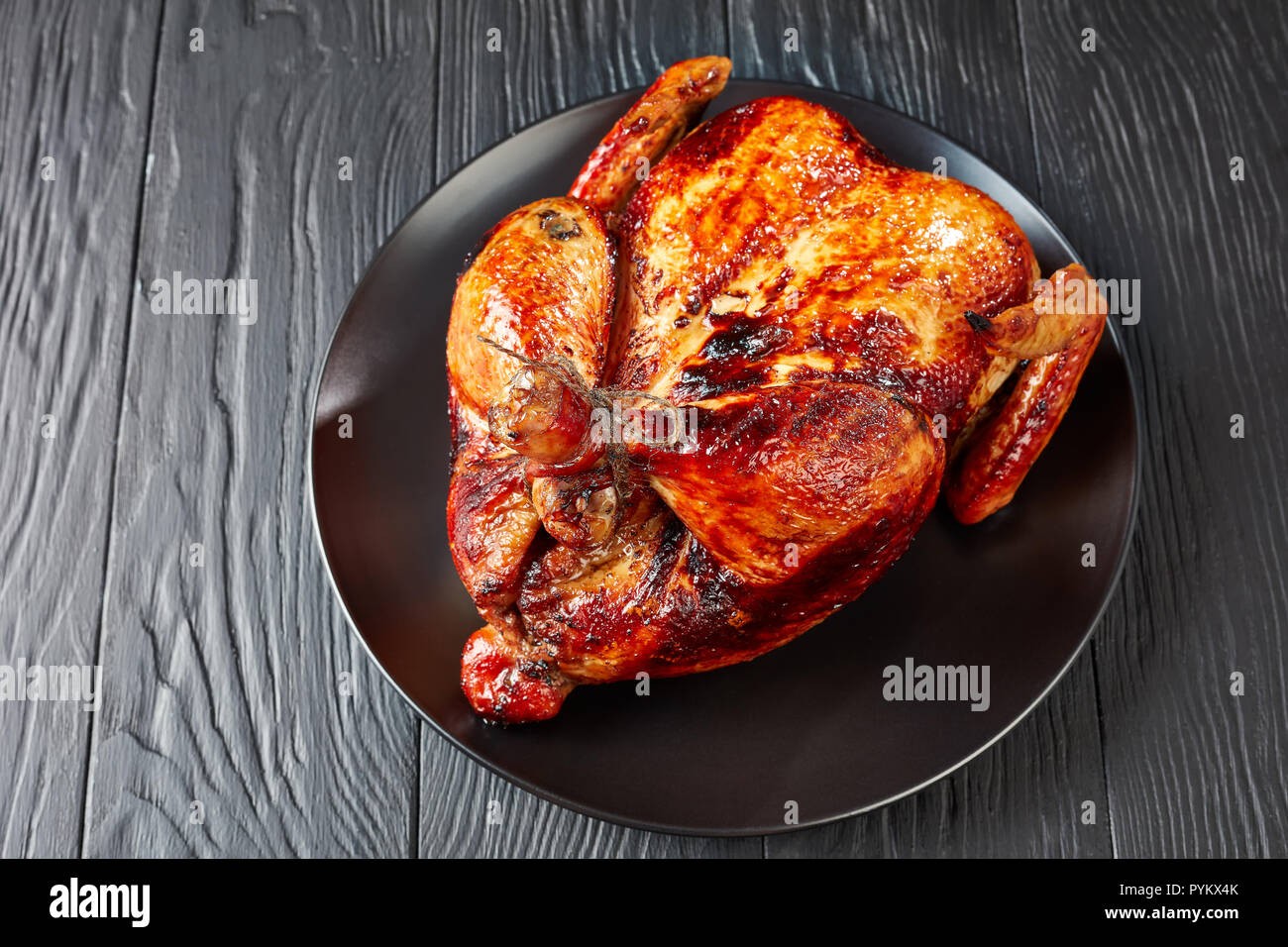 whole roasted chicken with golden brown crispy skin on a black plate on ...