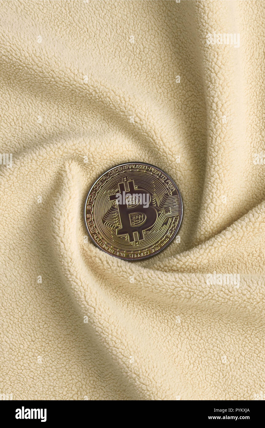 The golden bitcoin lies on a blanket made of soft and fluffy light ...