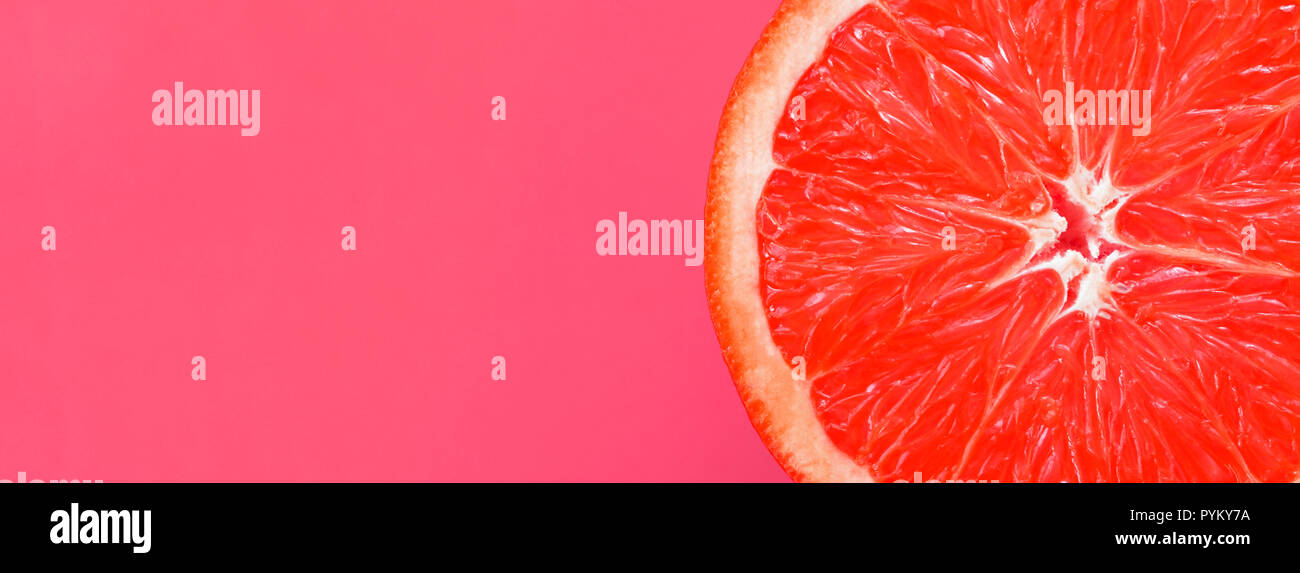 Top view of a one grapefruit slice on bright background in light pink ...