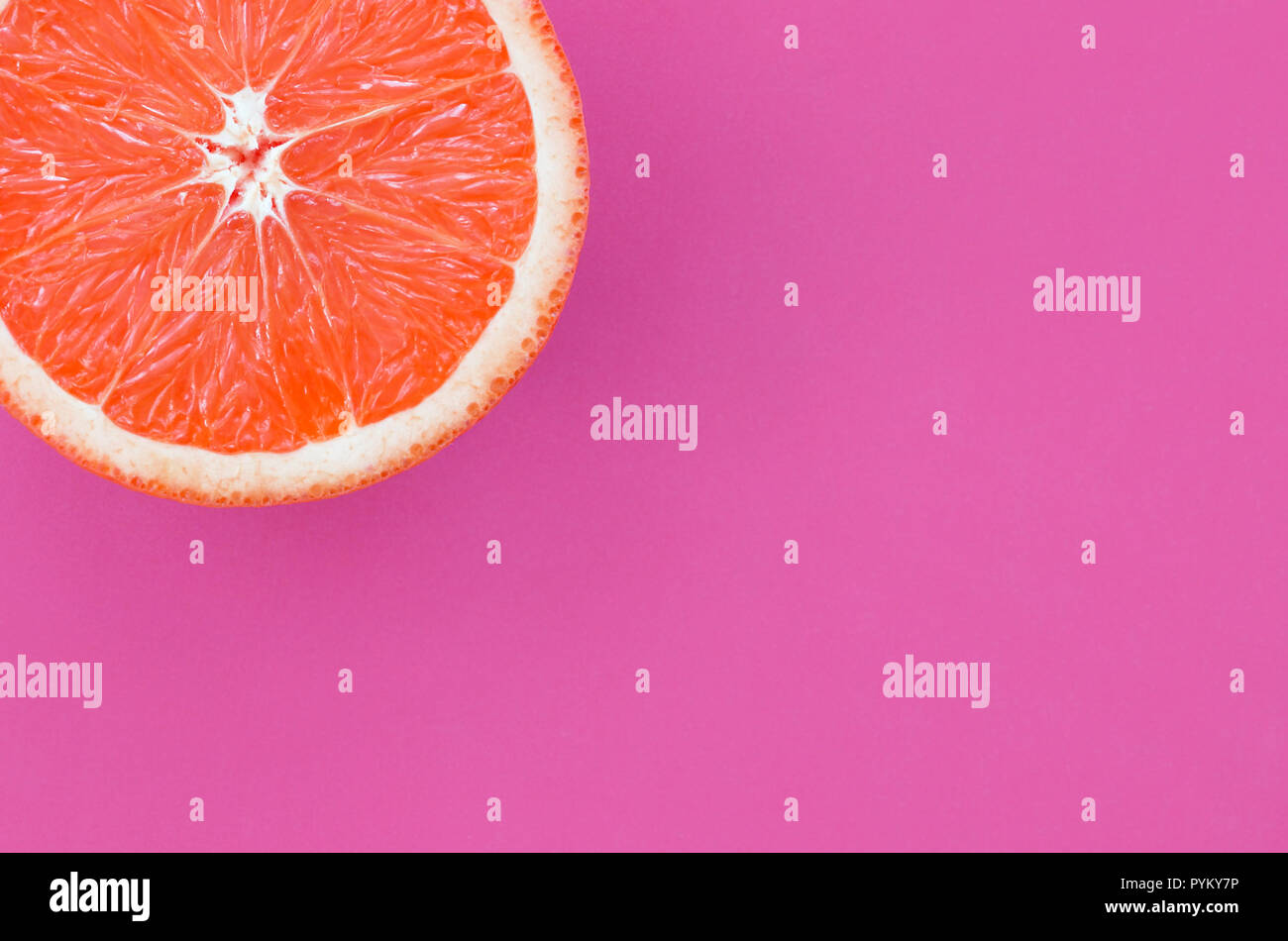 Top view of an one grapefruit slice on bright background in purple ...