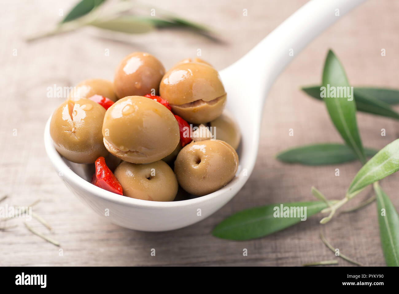 Split olives on white spoon and wood background. Spanish tapa Stock ...