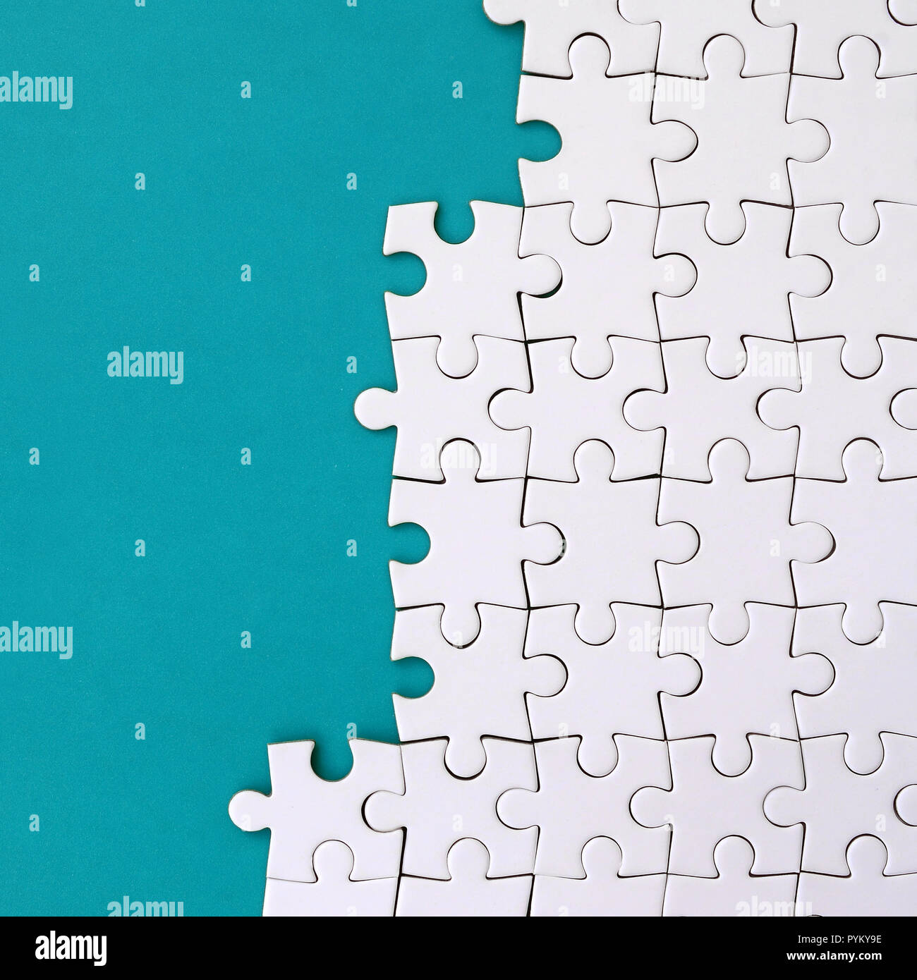 Fragment of a folded white jigsaw puzzle on the background of a blue ...