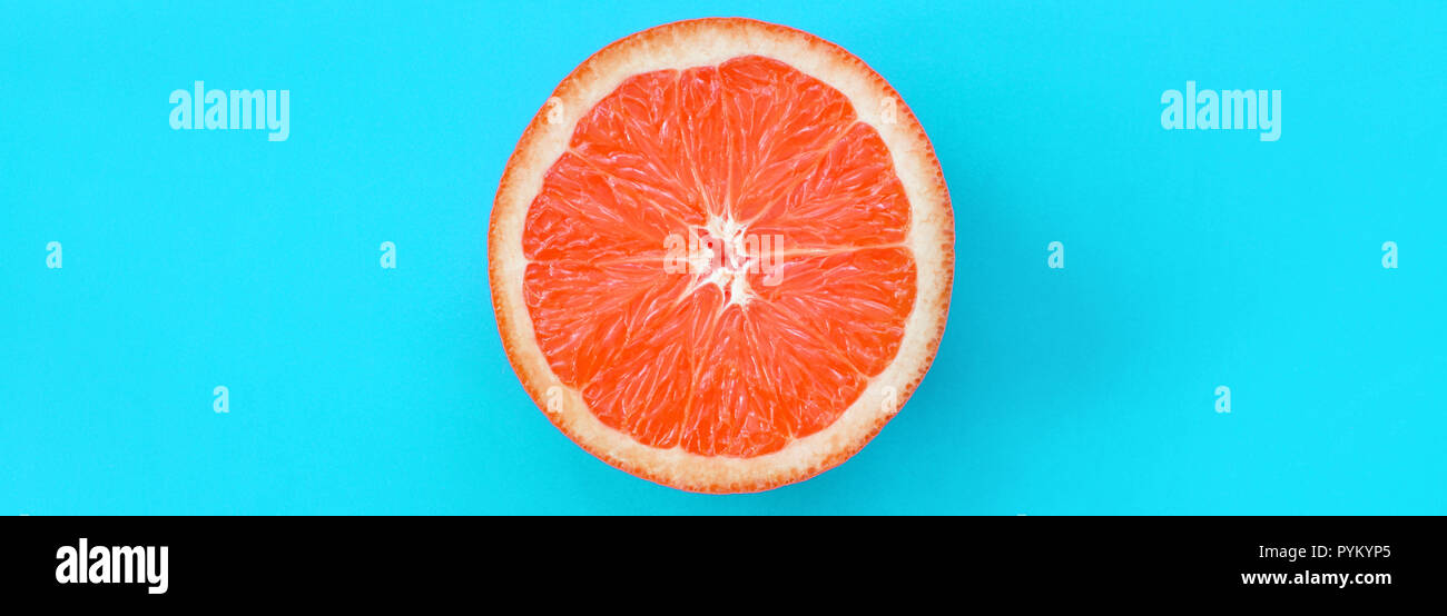 Top view of an one grapefruit slice on bright background in blue color ...