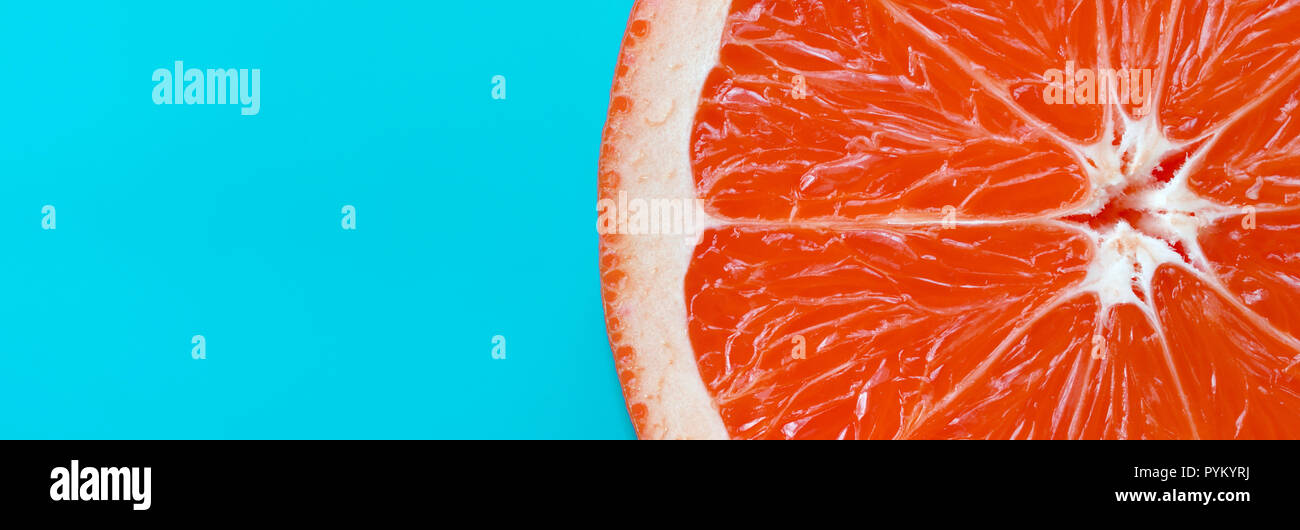 Top view of an one grapefruit slice on bright background in blue color ...