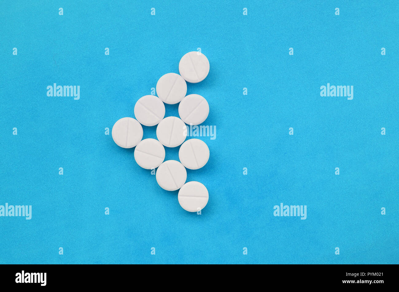 Several white tablets lie on a bright blue background in the form of a ...
