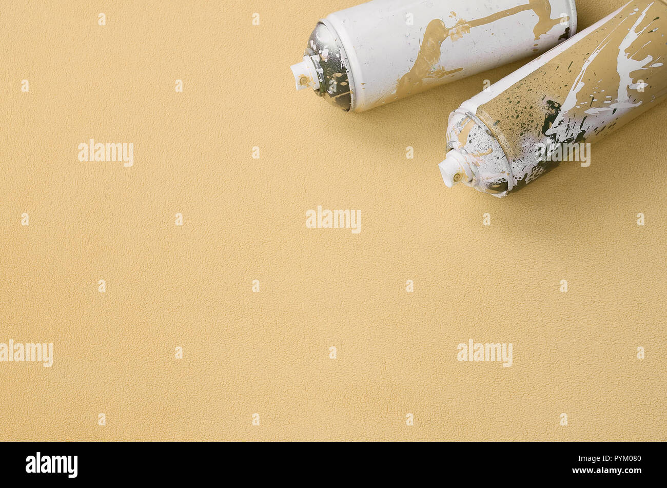 Some used blue aerosol spray cans with paint drips lies on a blanket of ...