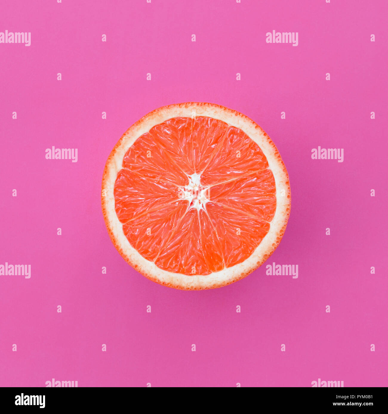 Top view of an one grapefruit slice on bright background in purple ...