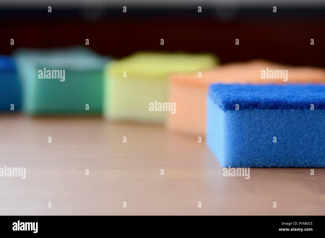 A few kitchen sponges lie on a wooden kitchen countertop. Colorful ...