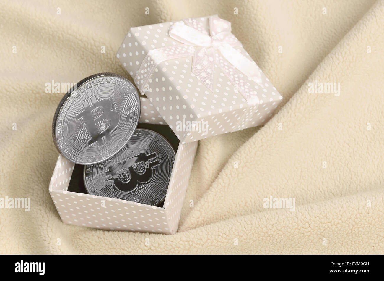 The silver bitcoin lies in a small orange gift box with a small bow on ...