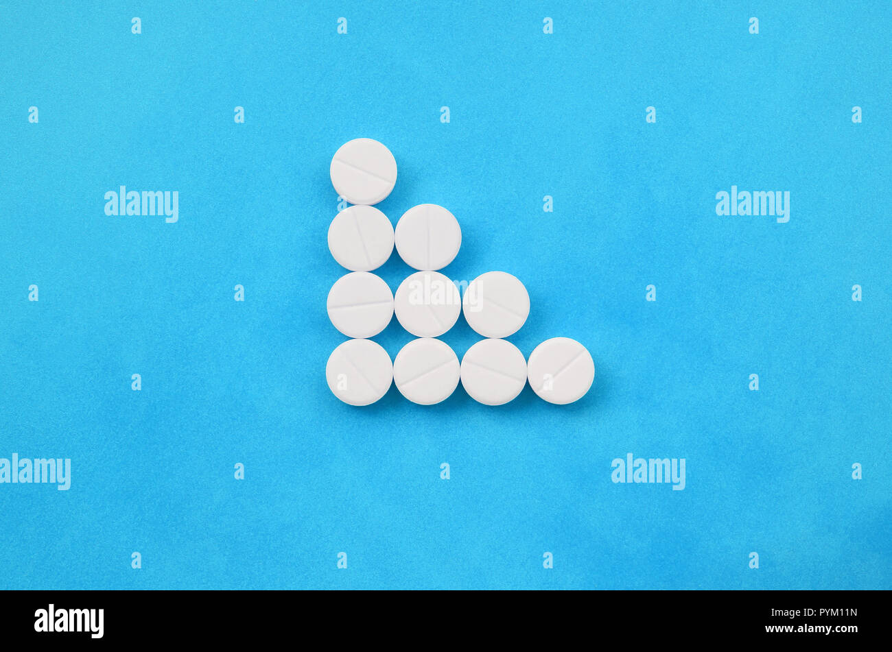 Several white tablets lie on a bright blue background in the form of a ...