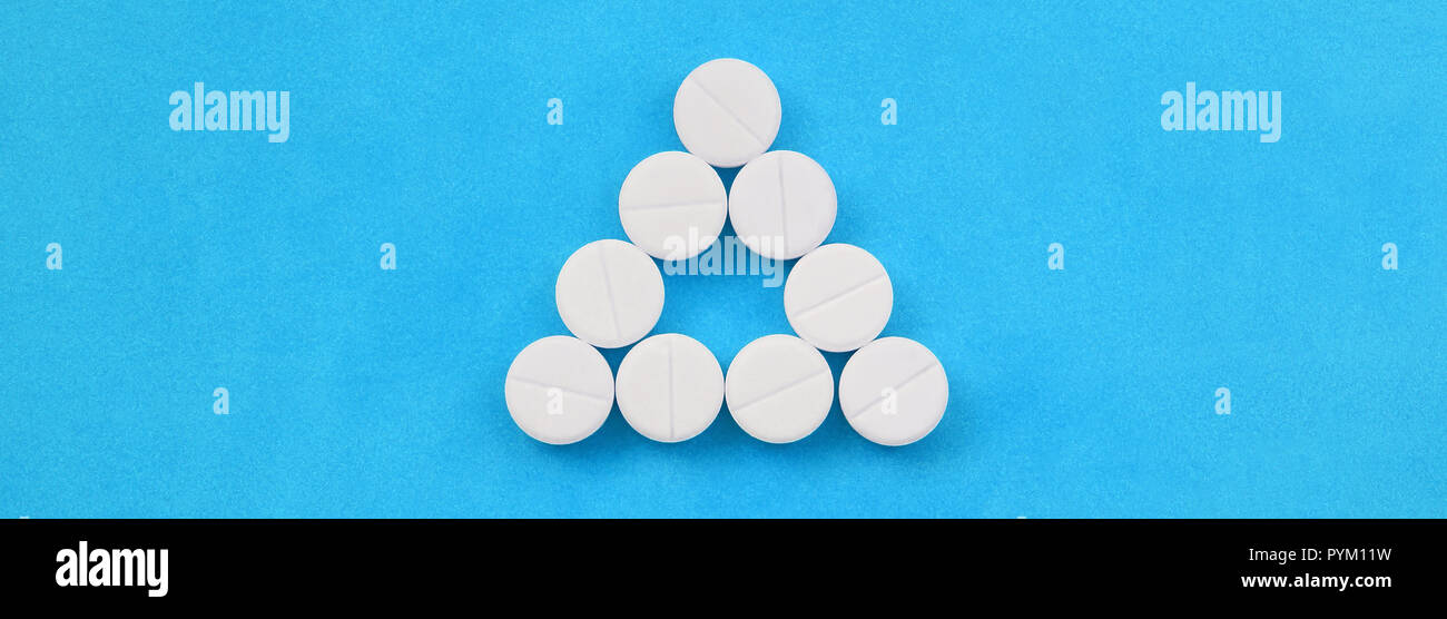 Several white tablets lie on a bright blue background in the form of an ...