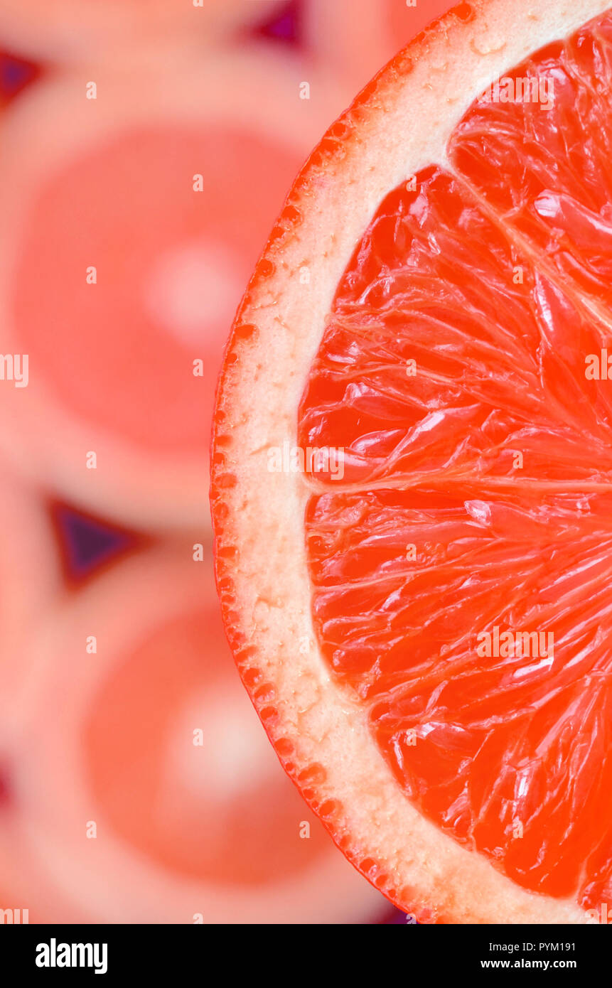 Top view of a fragment of the red grapefruit slice on the background of many blurred grapefruit ...