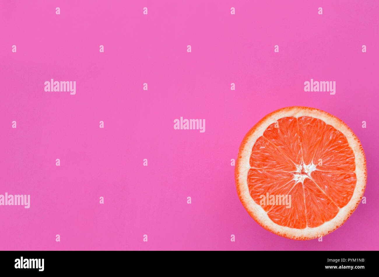 Top view of an one grapefruit slice on bright background in purple ...